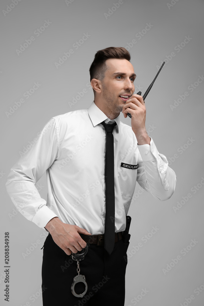 Male security guard using portable radio transmitter on color ...
