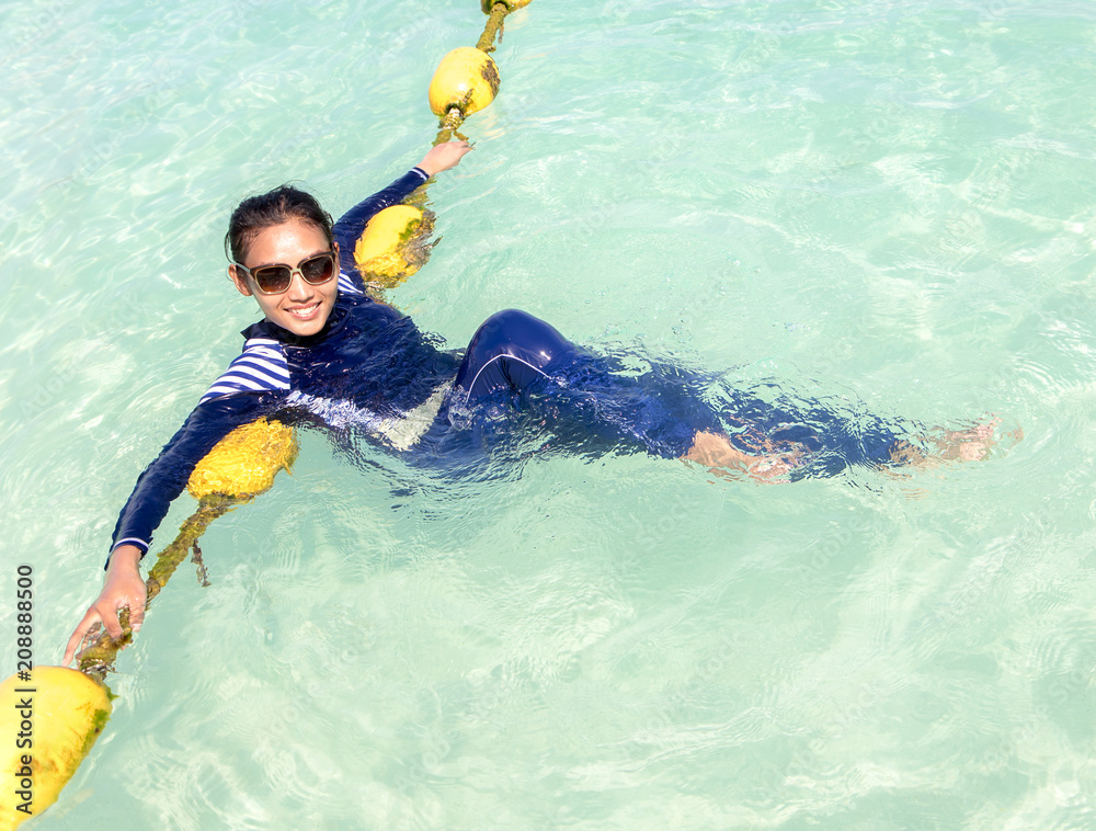 Foto de Woman in a full-body swimsuit lying on yellow buoys in the ...