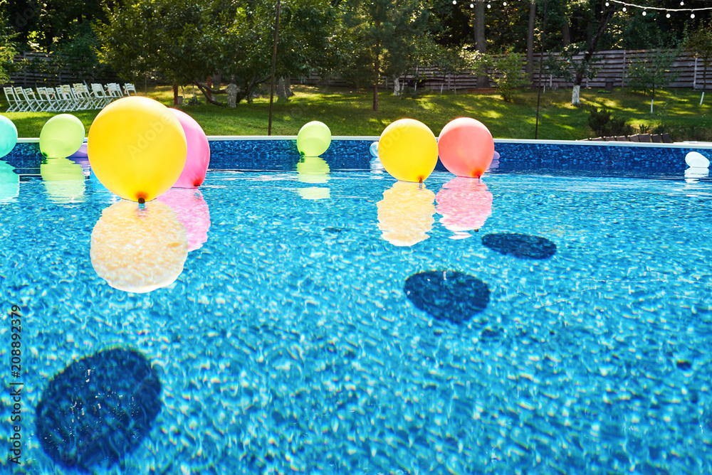 Swimming pool with colorful balloons on blue water outdoor, copy space ...