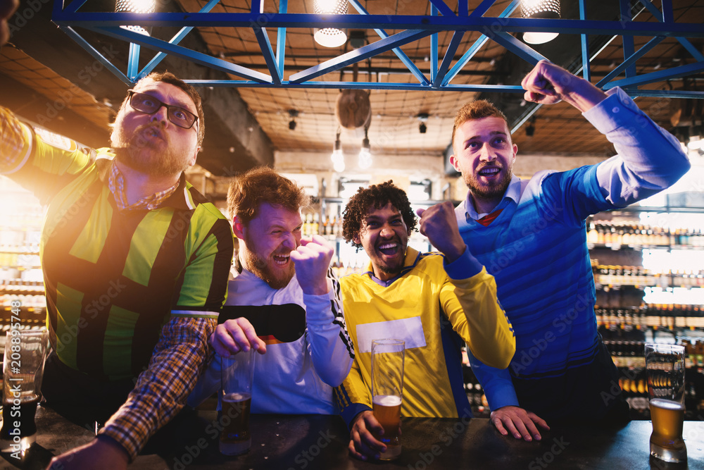 Passionate football fans are sitting at the counter of dimmed pub and ...