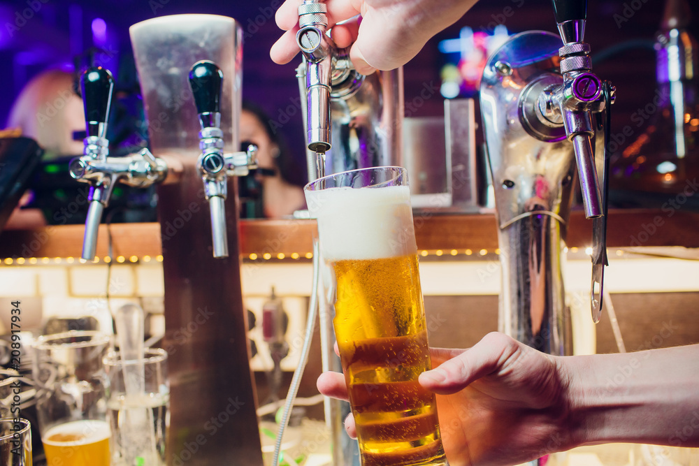 Young woman dispensing beer in bar from metal spigots. Beautiful female ...