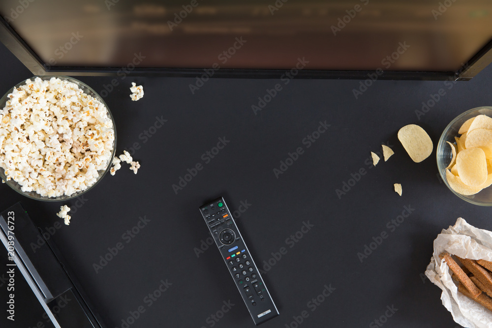 Popcorn, snack and a remote control for the TV, top view and flat lay ...