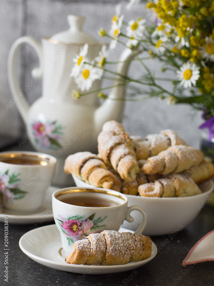 Croissants (bagels) with poppy seeds and tea on a bouquet of flowers ...
