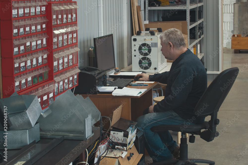 Adult man working at the computer at factory of production CNC machine ...
