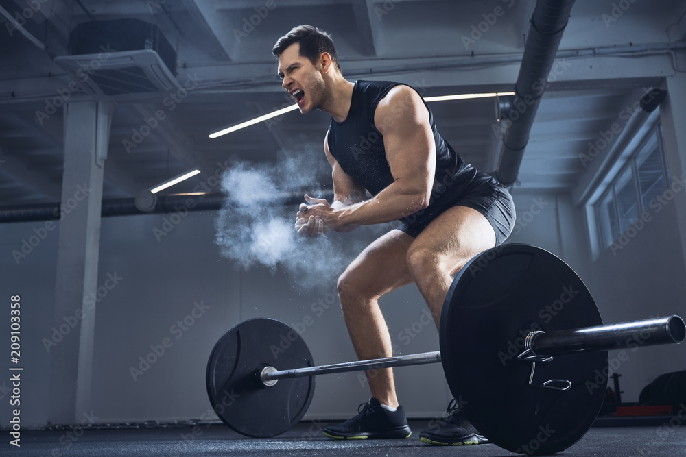 Motivated weightlifter clapping hands before barbell workout at gym ...