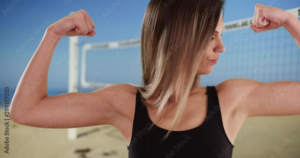 Athletic young woman flexing and kissing biceps outdoors in beach ...