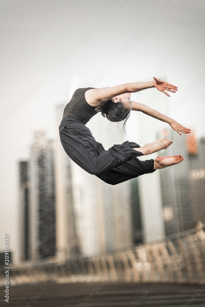 Cute Young woman athlete performs a perfect straddle leap high up, with ...