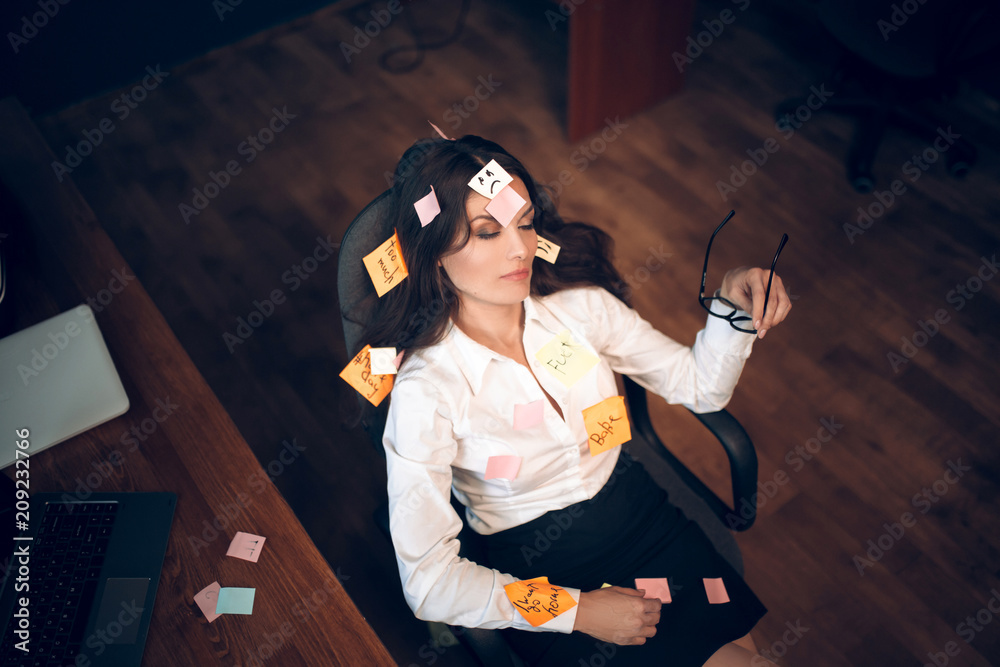 Pretty sleepy business lady spinning in her chair covered in post it ...