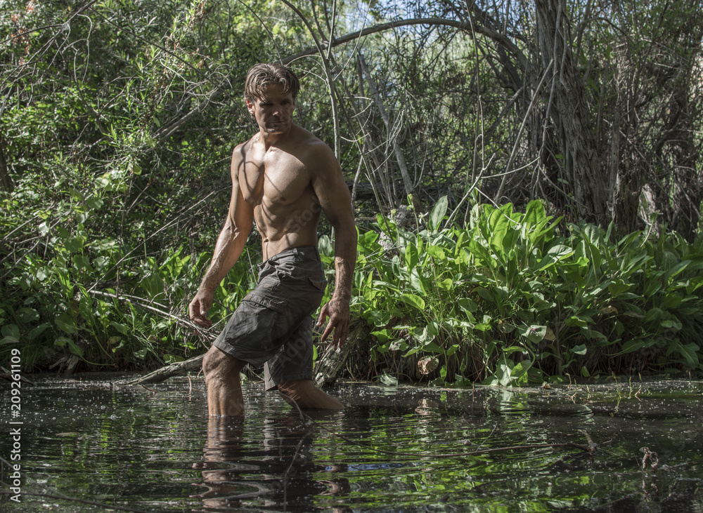 Sexy adventure man wading through swamp Stock Photo | Adobe Stock