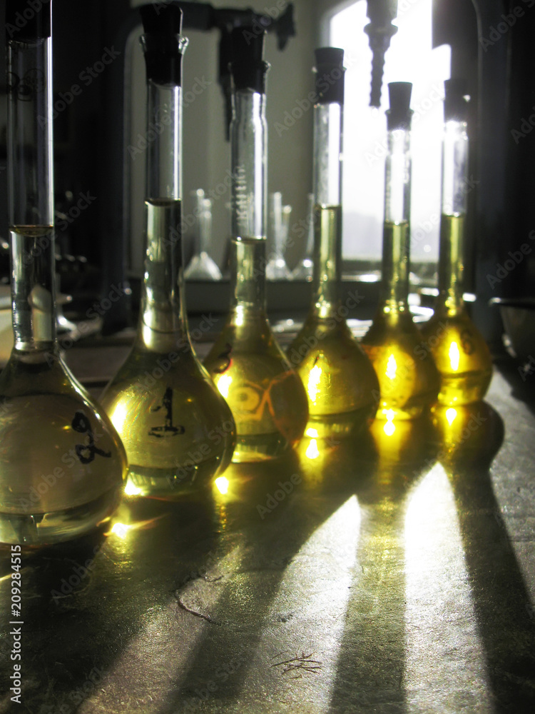 A raw of measuring flasks filled with yellow liquid and closed with ...