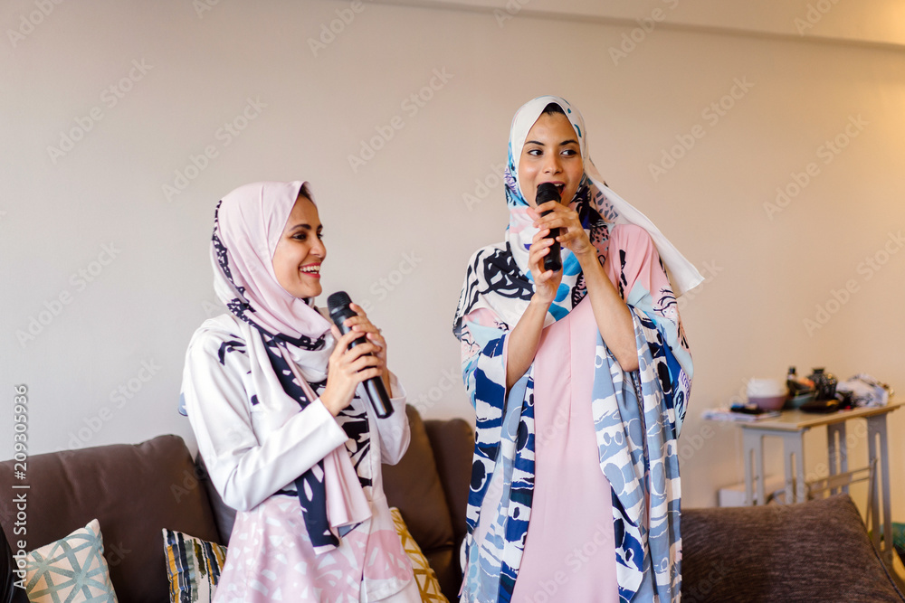 Two Muslim Malay women unwinding and relaxing as they enjoy singing in ...