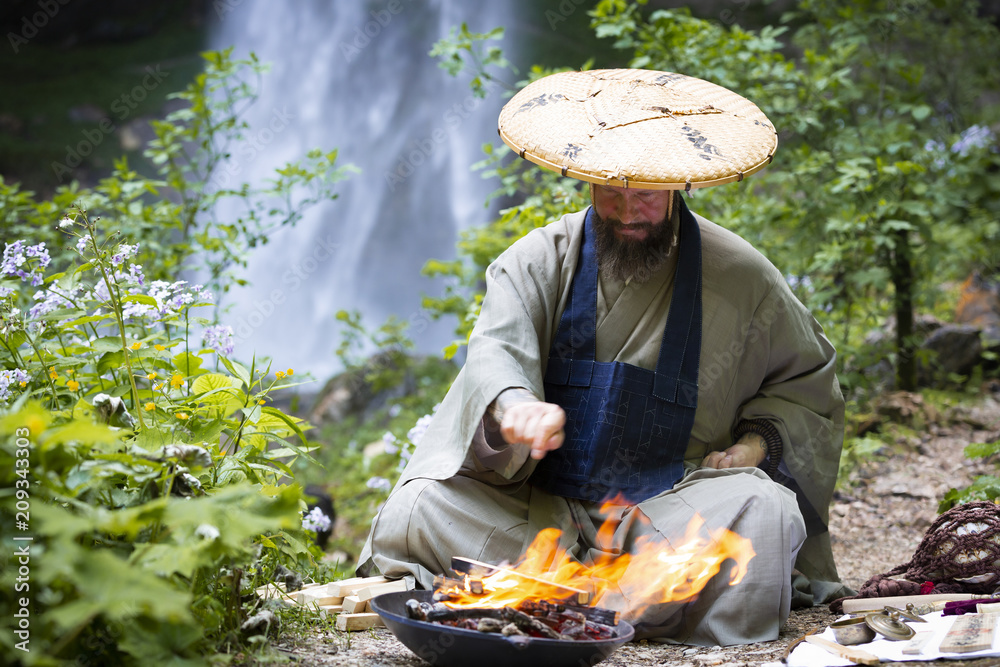 European man with beard and japanese robe makes fire ceremony in front ...