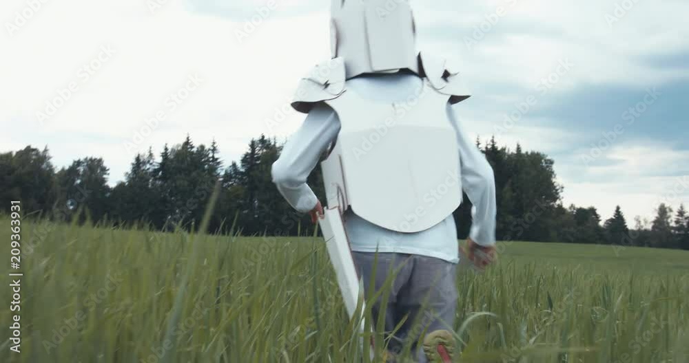 Kid boy wearing cardboard medieval knight armor costume chasing his ...