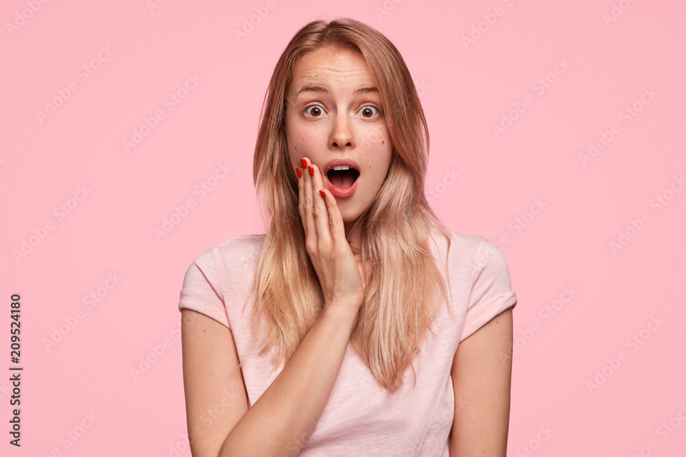 Stunned beautiful female model expresses surprisement as recieves ...