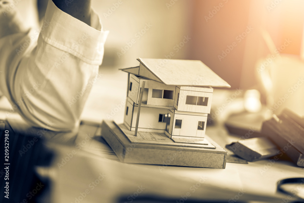 house design concept with designer hand with house model and drawing ...