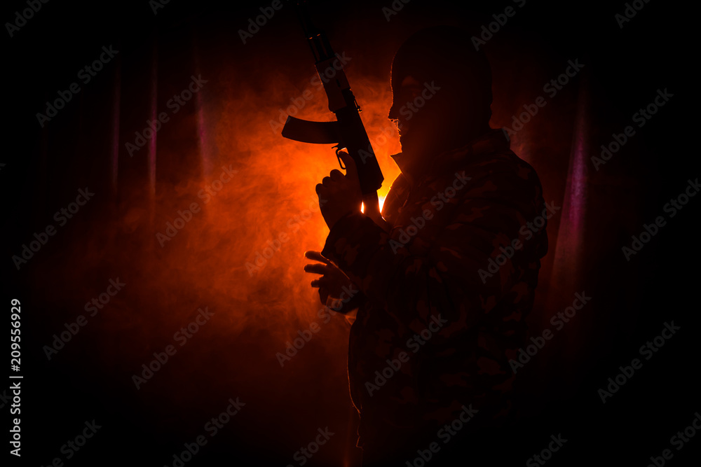 Silhouette of man with assault rifle ready to attack on dark toned ...