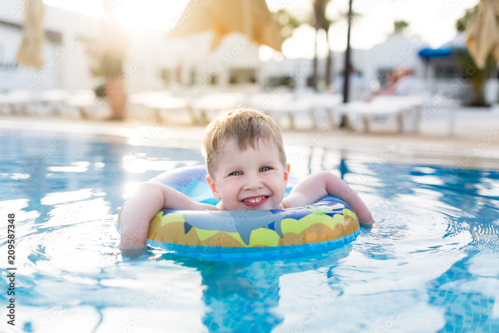 Little three years old kid boy swimming and splashing in swimming pool ...