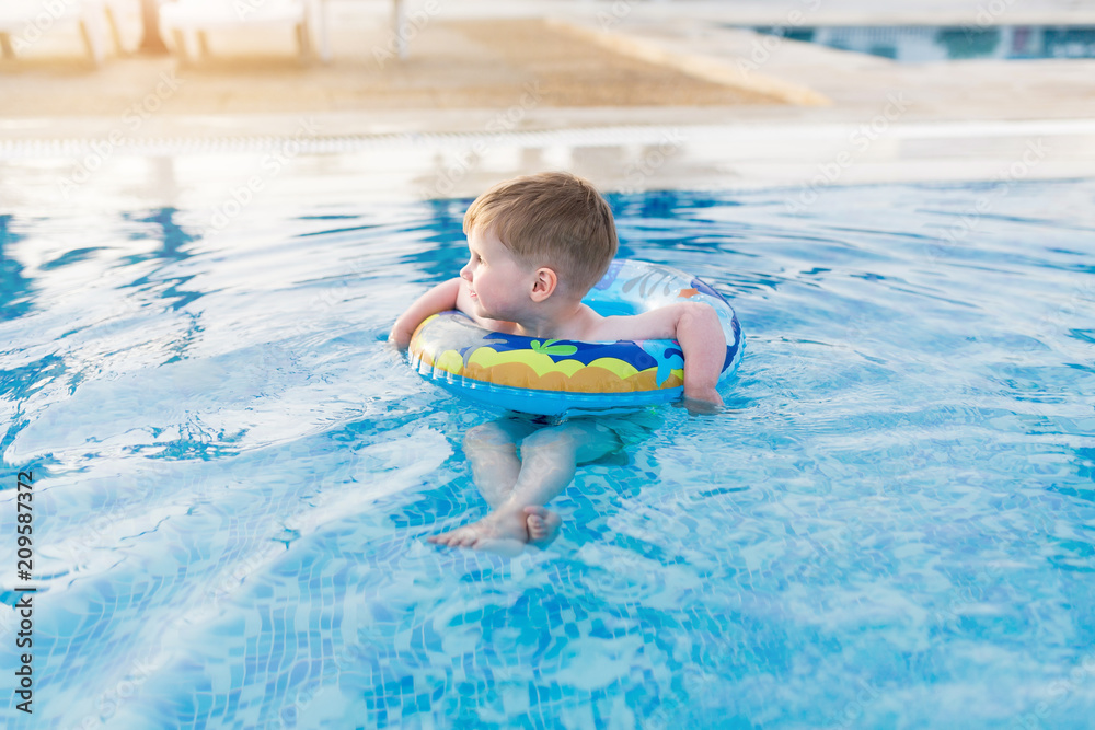 Little child boy swimming and playing in a open pool with happy smile ...