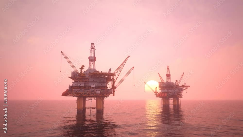 Two offshore platforms in the open sea with a pink evening sky and ...