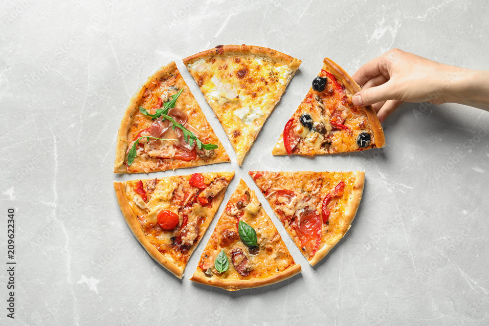 Woman taking slice of delicious pizza on light background, top view ...