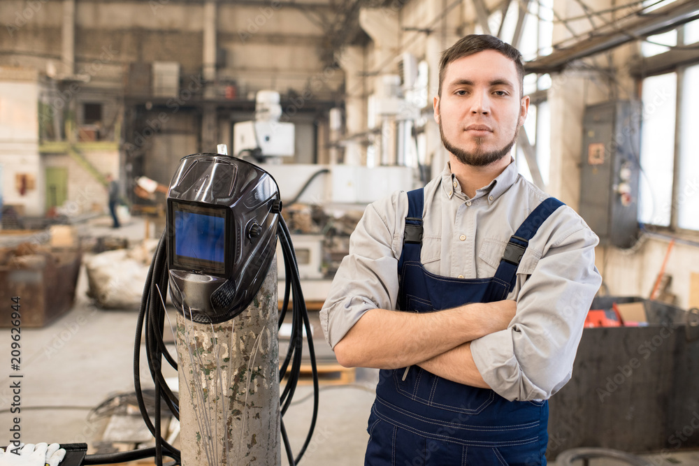 Serious confident bearded young high professional welder with crossed ...