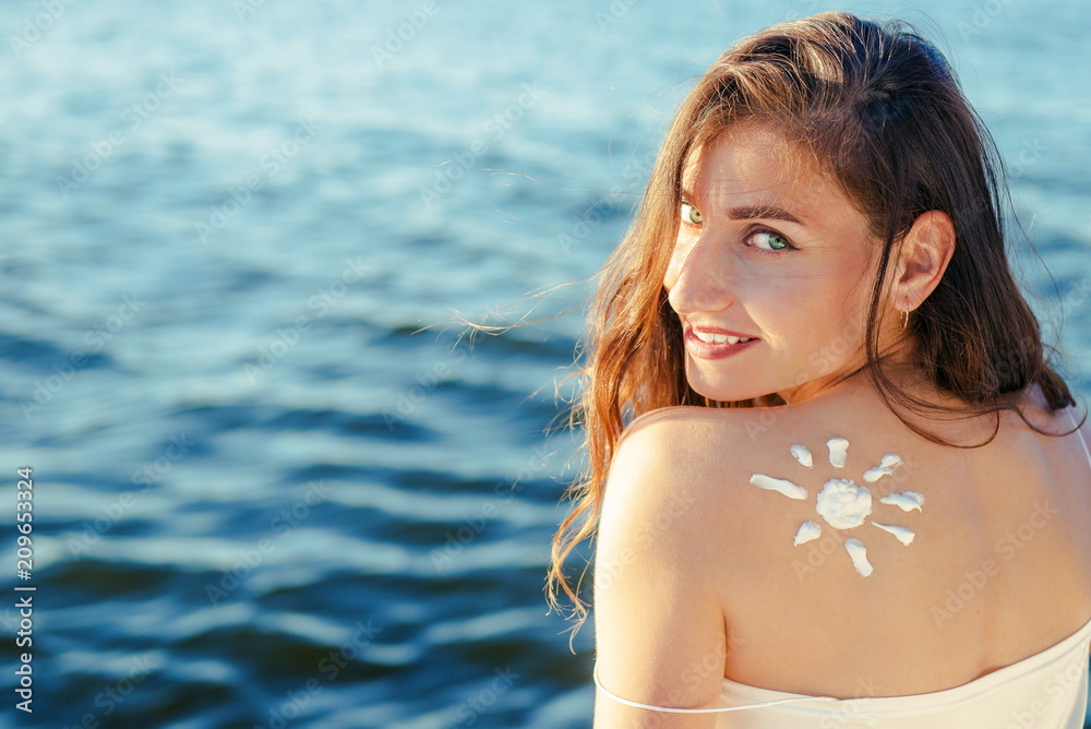 Sunbath protection. Woman using sun cream on the beach. Sun on a girl's ...