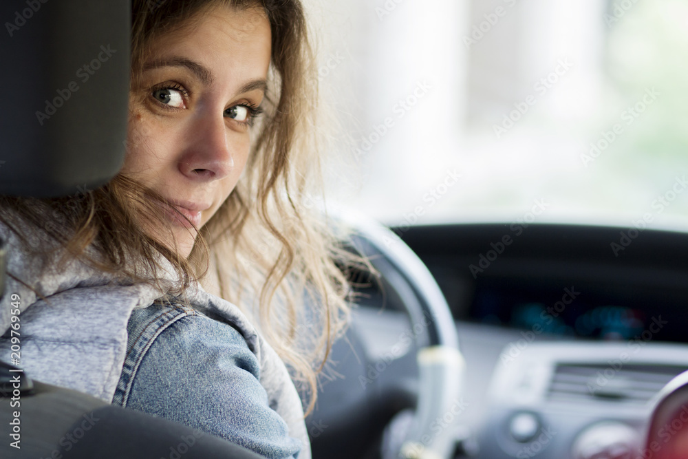 Girl driving car. Young woman behind driver's seat looking at car's ...