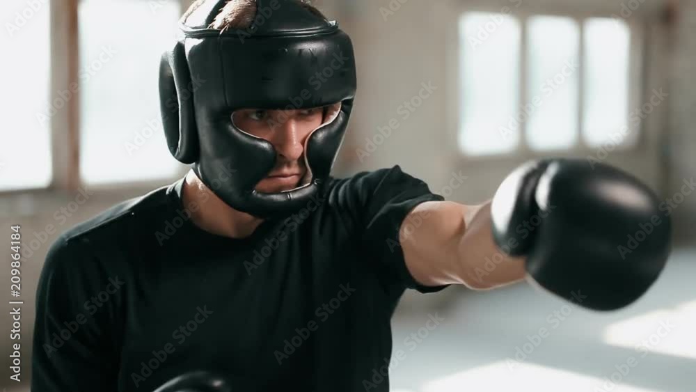 Aggressive boxer practises different punching techniques, wearing black ...