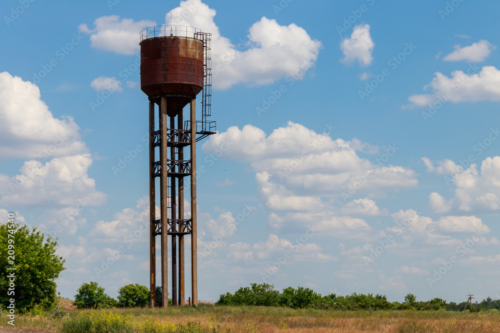 Old rusty water tower in the green field Stock Photo | Adobe Stock