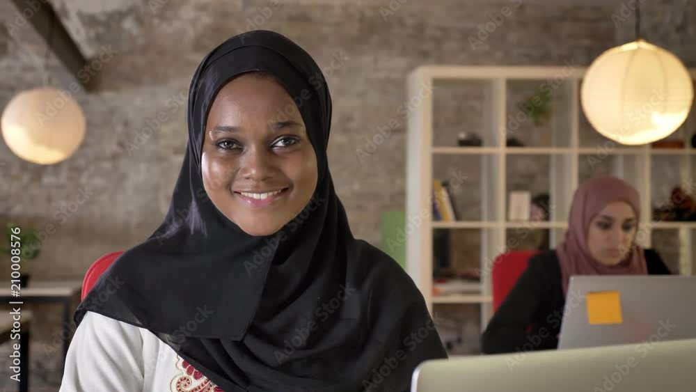 Portrait of young black muslim women in hijab working and smiling ...