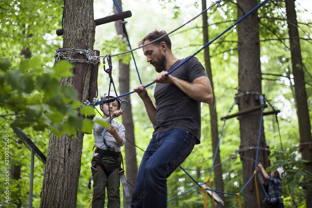 boy enjoys climbing in the ropes course adventure. smiling child ...