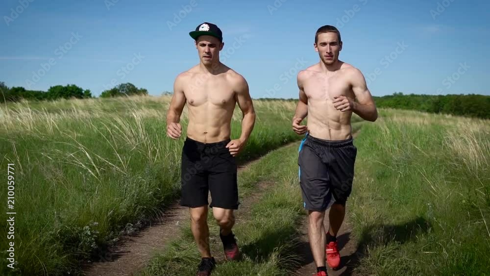 Vidéo Stock Two shirtless muscular men exer ising in nature in ...