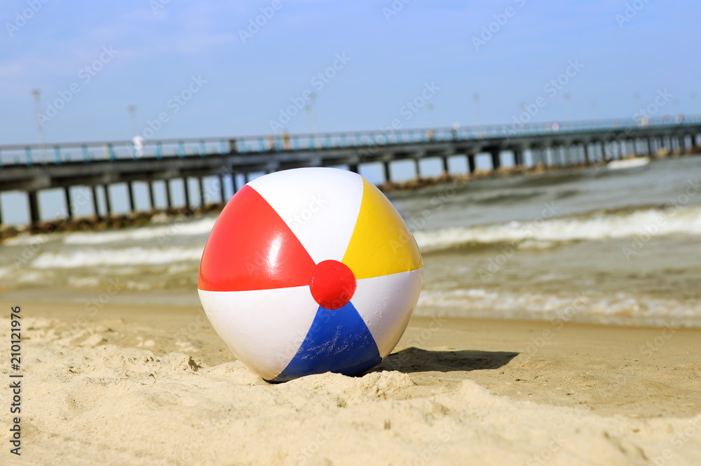Colorful beach ball on sand and waving sea. Holiday beach ball near ...