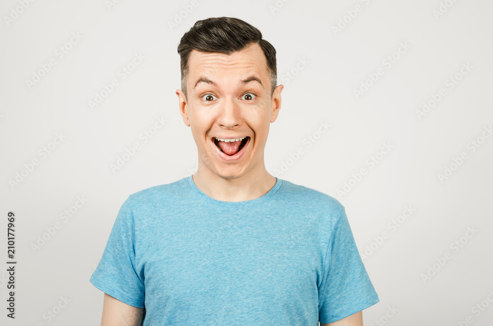 Young smiling guy with an open mouth, dressed in a blue T-shirt on a ...