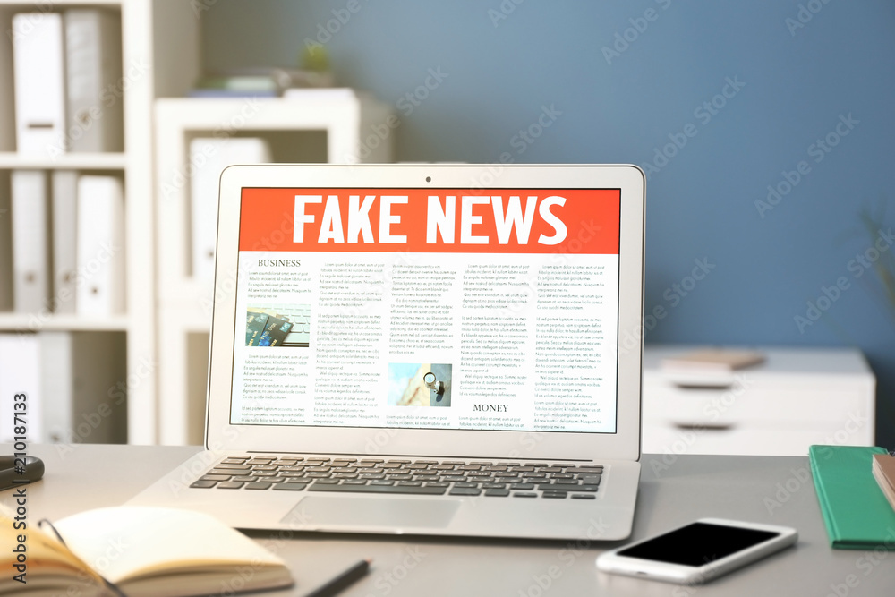 Workplace with laptop and fake news on screen Stock Photo | Adobe Stock