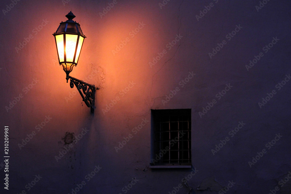 Night view of the illuminated plaster wall with old fashioned street ...