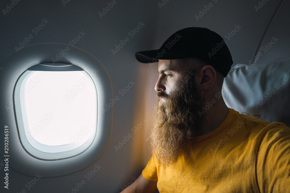 Man looking through window while traveling by an airplane Stock Photo ...
