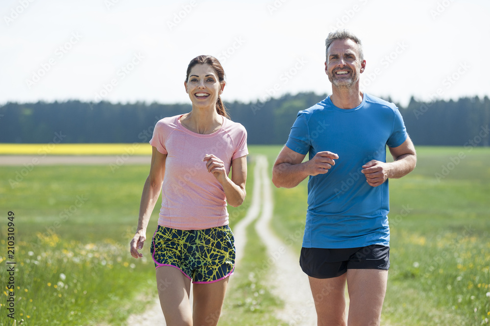 Couple running on field path Stock-Foto | Adobe Stock