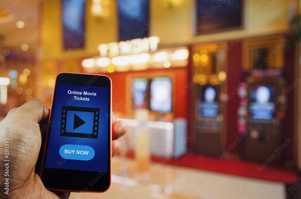 hand using mobile smart phone to buy cinema tickets with blurred image ...