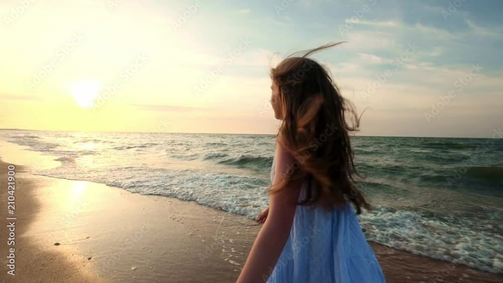 SLOW MOTION: Girl running in shallow water at sunset. A girl in a white ...