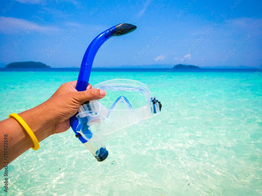 Vacation tropical beach background with man hand holding dive mask and ...
