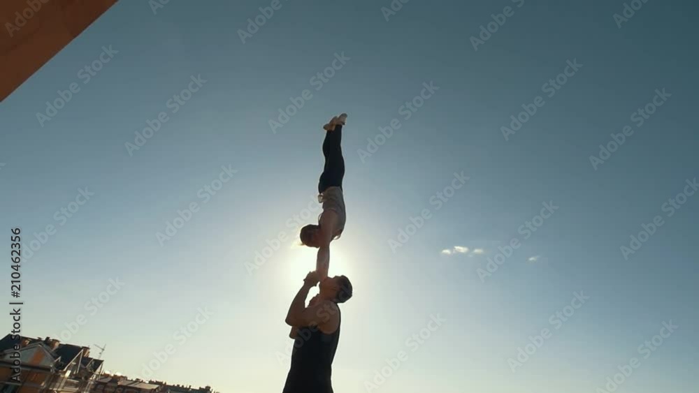 Young acrobatic couple performing flip, young man throws a woman in the ...