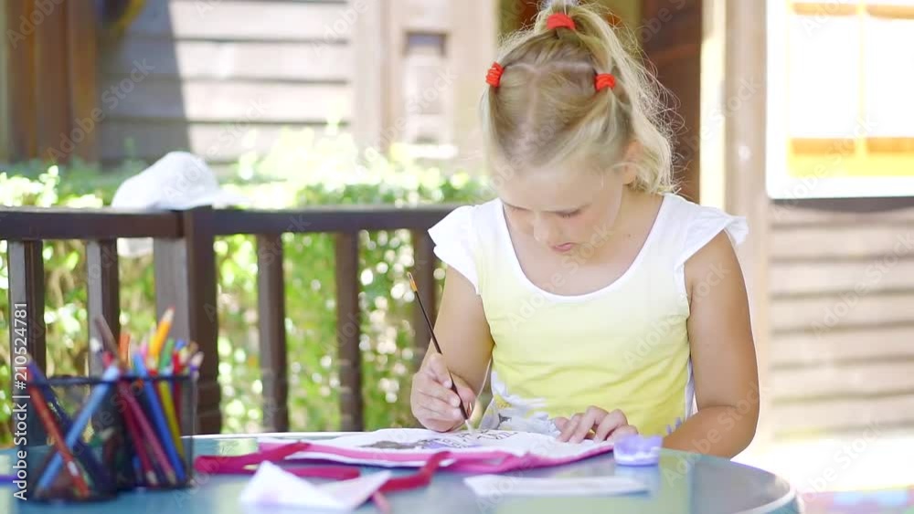 funny and calm girl is engaged in drawing paints at the desk on the ...
