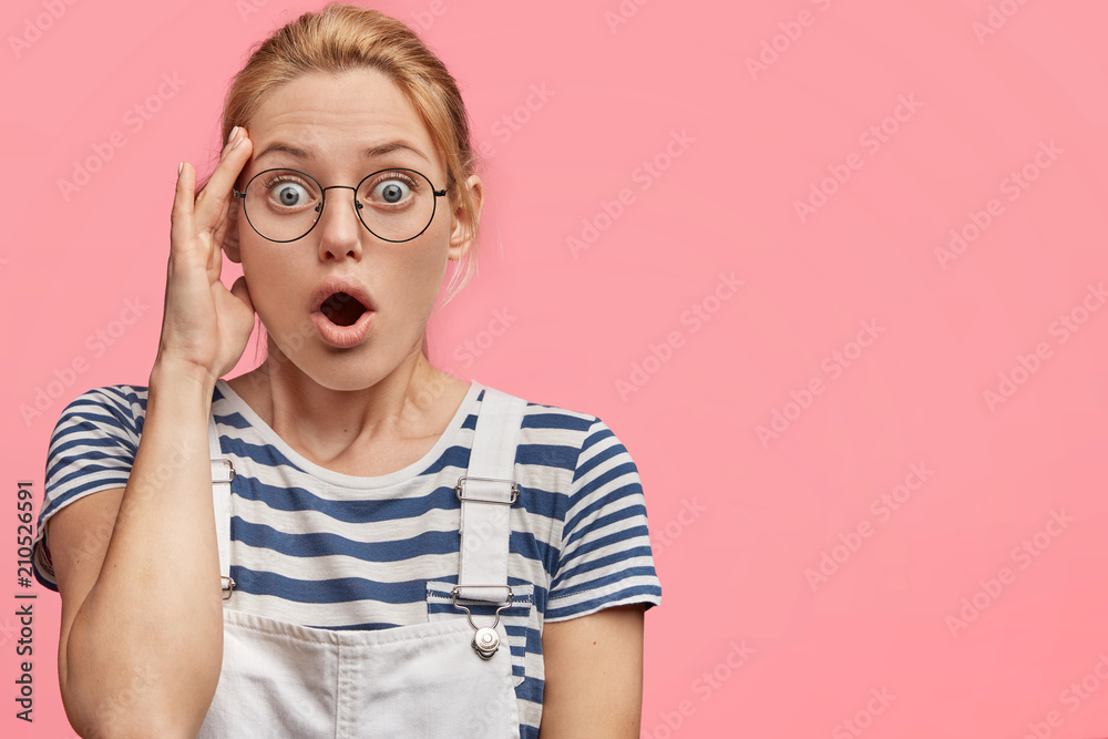 Puzzled beautiful young female looks with scared shocked expression ...