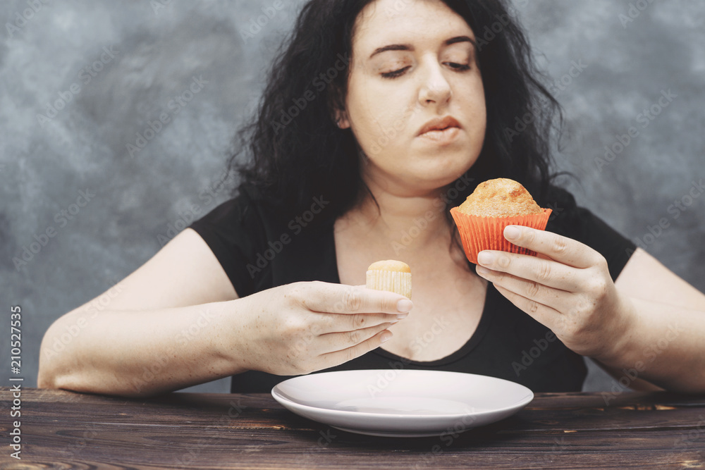 Overweight woman choosing between little and big muffins. Sense of ...