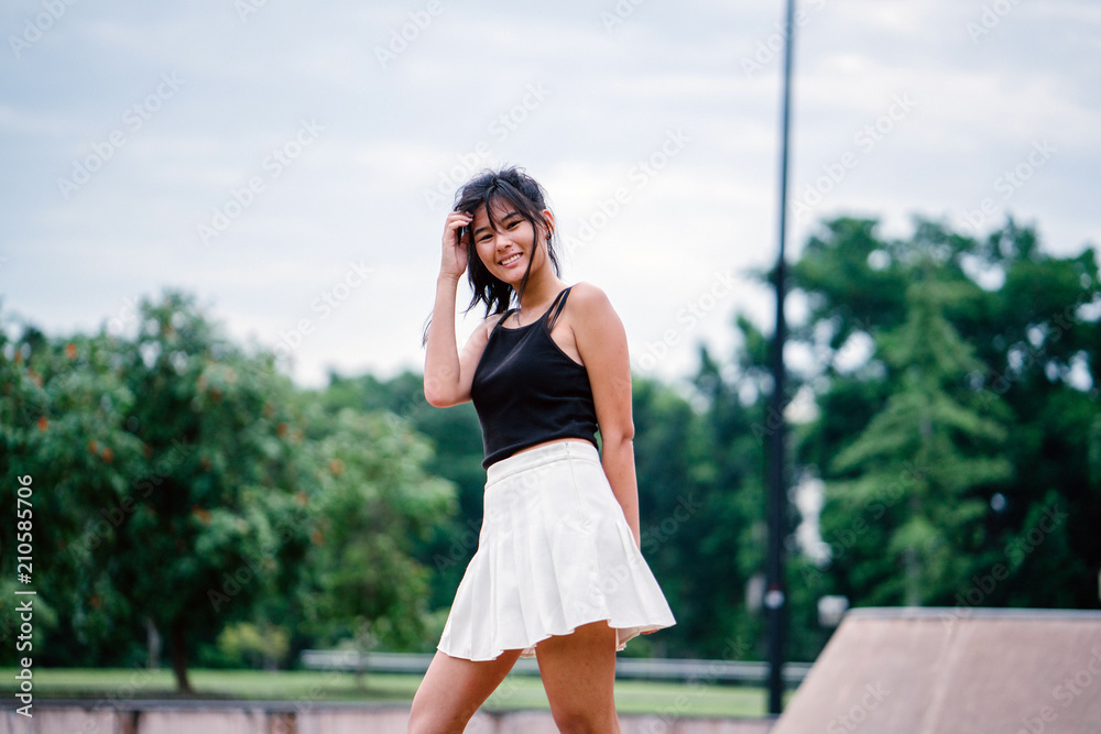 A portrait of a young Chinese Asian skater girl in a tank top and white ...
