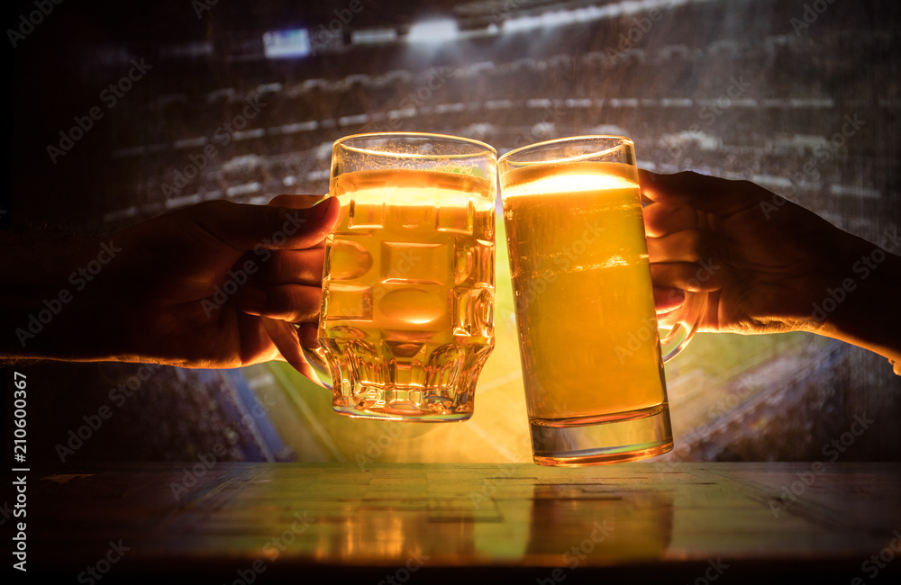 Two friends toasting (clinking) with glasses of light beer at the pub ...