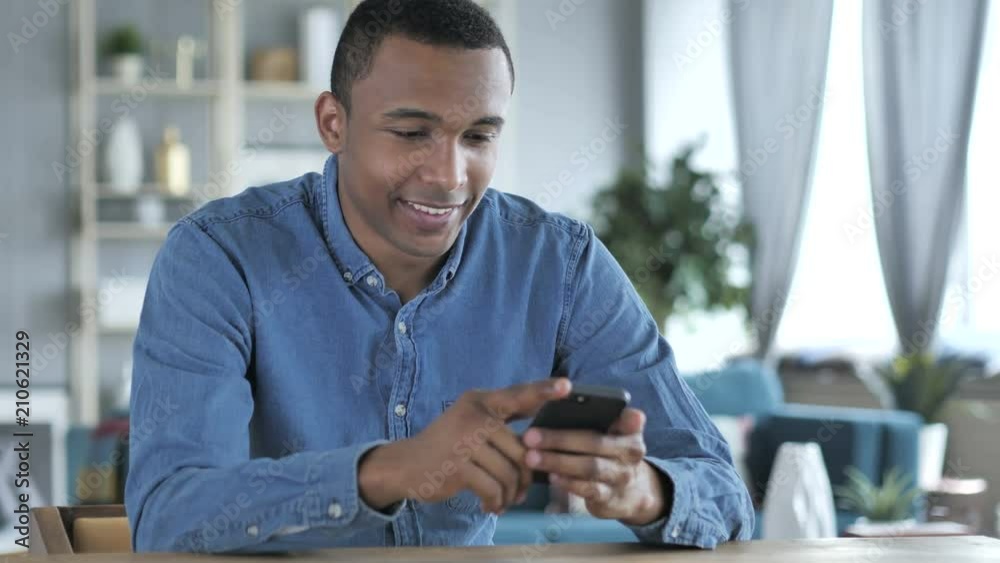 Young African Man Using Smartphone at Workplace Stock Video | Adobe Stock