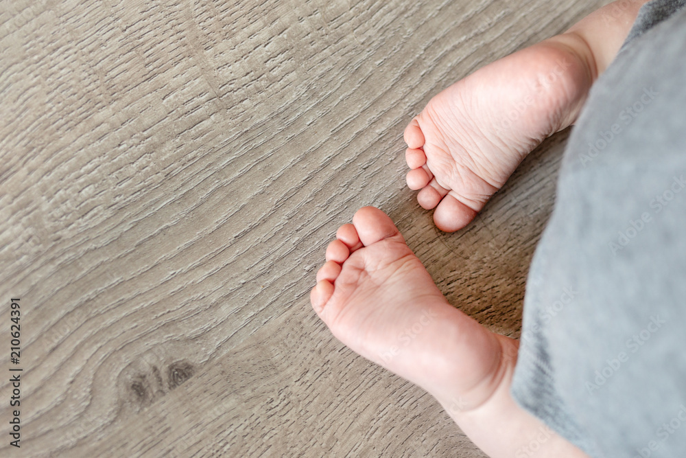 Close-up cute infant baby feet on wooden floor background. Funny ...