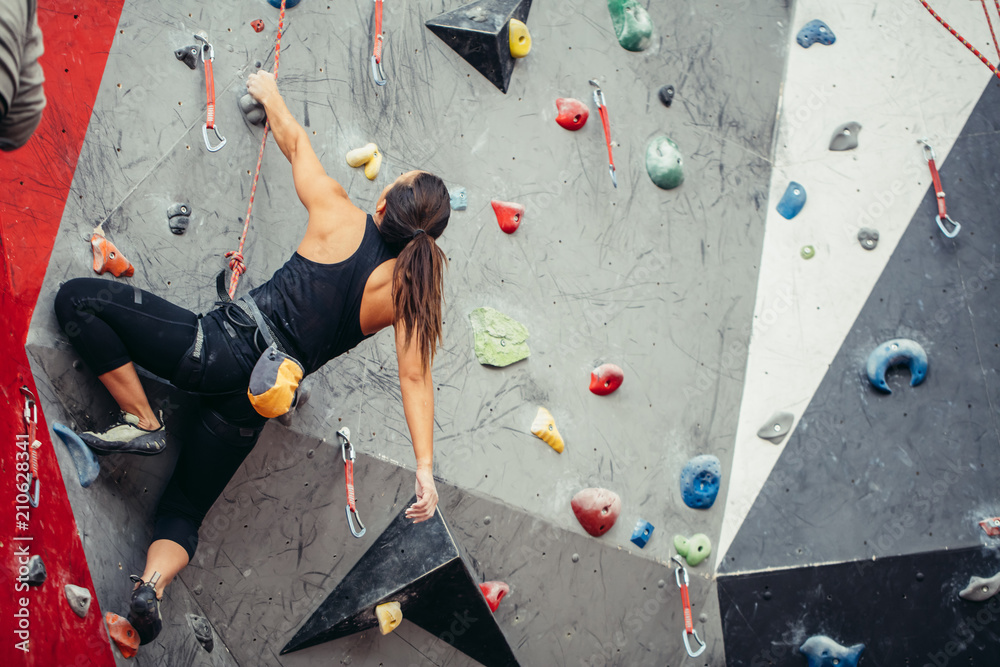Fit sporty student girl equipped with safety rope and harness moving up ...